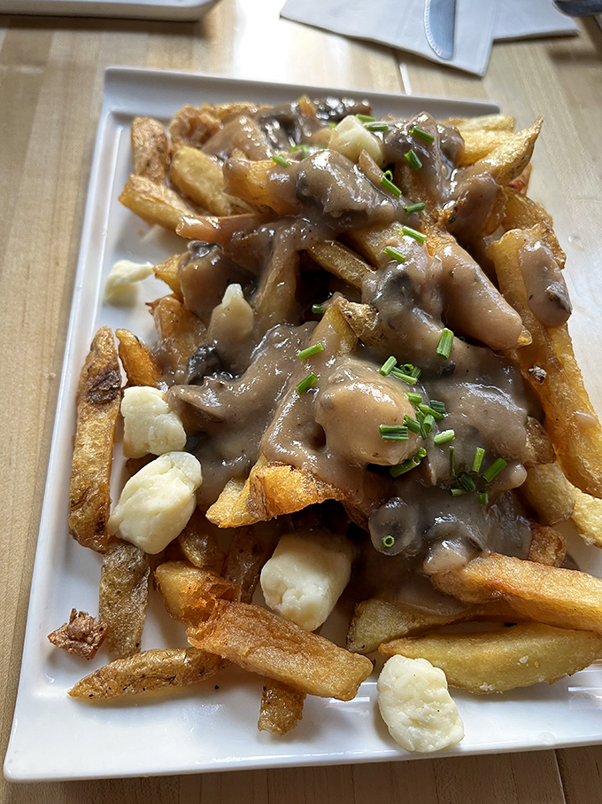 Poutine perfection! This mountain of crispy fries, savory gravy, and squeaky cheese curds is the comfort food hug your taste buds didn't know they needed.