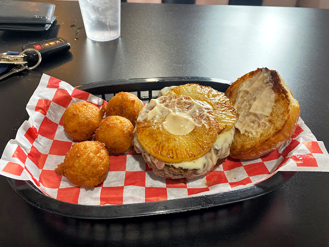 Meet the burger that launched a thousand cravings. With a side of hush puppies, it's a plate that screams "Comfort food jackpot!"
