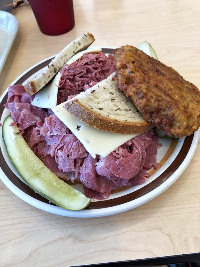 The Leaning Tower of Deli! This corned beef sandwich defies gravity and common sense, flanked by a crispy potato pancake sidekick.