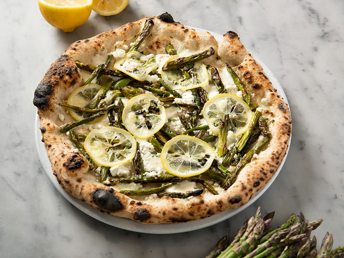 Spring has sprung on this pizza! Asparagus and lemon slices dance atop a perfectly blistered crust, proving that vegetables can party just as hard as pepperoni.