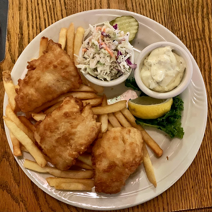 The holy trinity of comfort food: crispy fish, golden fries, and tangy slaw. It's like a beach vacation for your taste buds, minus the sand.