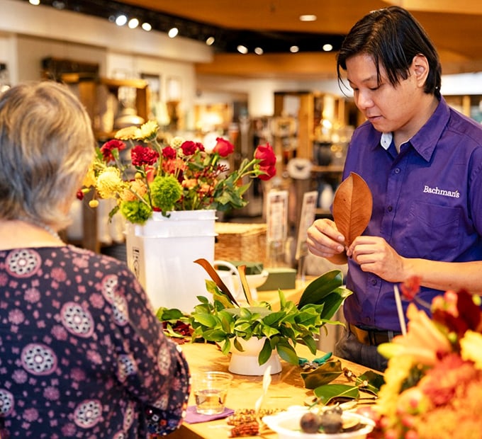 The plant whisperer at work! This Bachman's staff member is crafting floral magic &ndash; it's like watching Bob Ross paint, but with petals instead of paint.