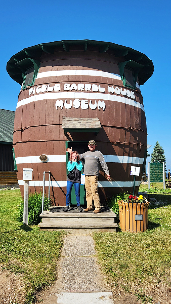 "Honey, I shrunk the tourists!" Visitors pose gleefully, dwarfed by the massive pickle barrel entrance.