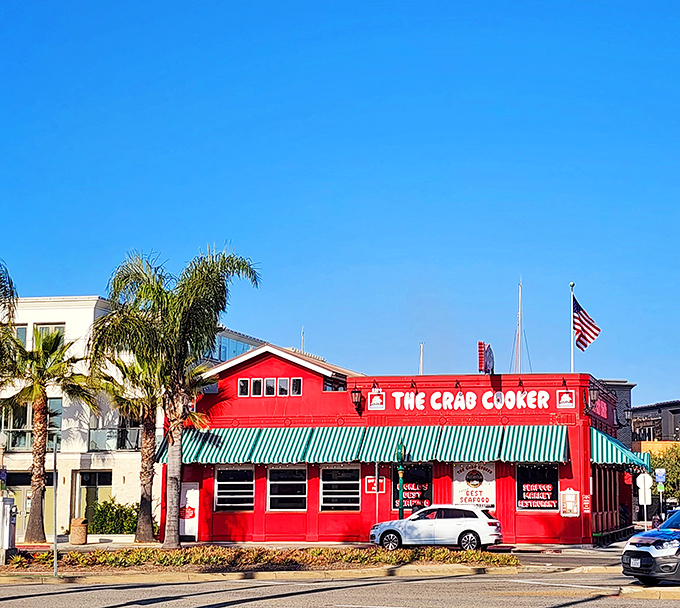 A crimson beacon of seafood delight! The Crab Cooker's exterior is as bold as its flavors, with a cheeky sign that dares you not to look up.