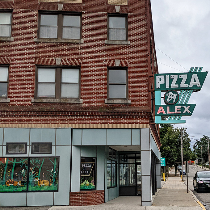 A slice of nostalgia! Pizza By Alex's vintage sign beckons like a neon-lit time machine, promising cheesy delights and a trip down memory lane.