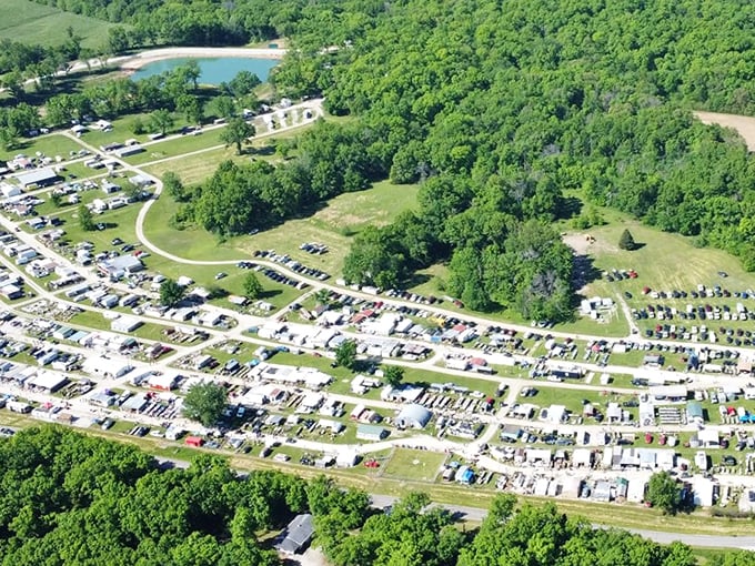 Aerial view of Rutledge Flea Market: a sprawling maze of vendors, vehicles, and bargain hunters nestled in lush greenery. A treasure hunter's paradise from above, where deals and adventures await.