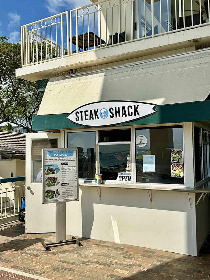 Surf's up, and so is your appetite! The Steak Shack's surfboard sign promises waves of flavor just steps from Waikiki Beach.