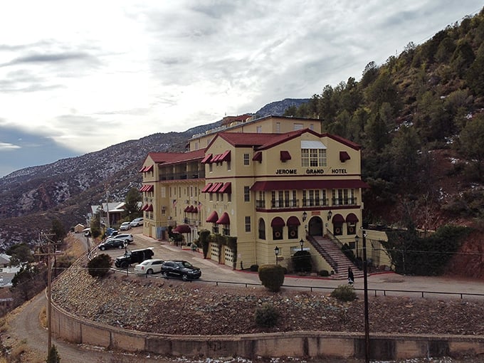Perched like a watchful sentinel, the Jerome Grand Hotel stands tall, its yellow facade and red trim a beacon of mystery against the rugged Arizona landscape.