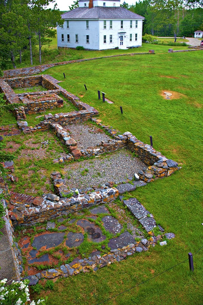 A white colonial house stands tall, its pristine facade a stark contrast to the ancient stone ruins at its feet. History's layers unfold before your eyes!