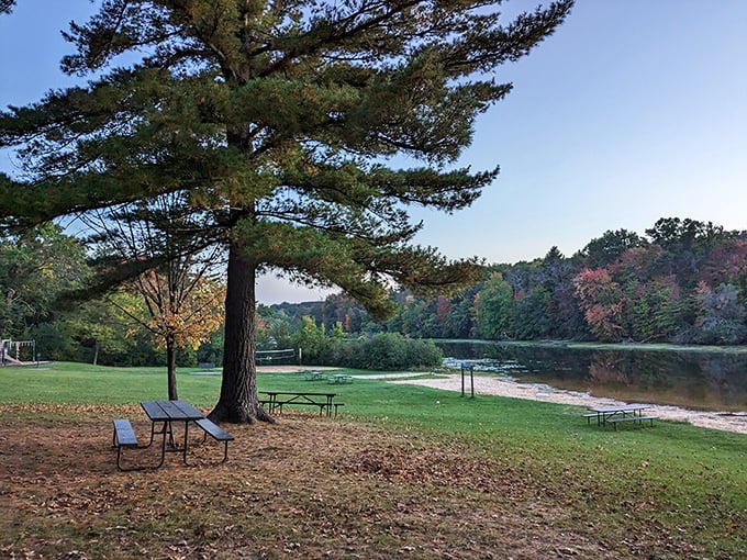 Tranquil lakeside picnic area at Mirror Lake State Park, where autumn's touch begins to paint the surrounding forest in warm hues.