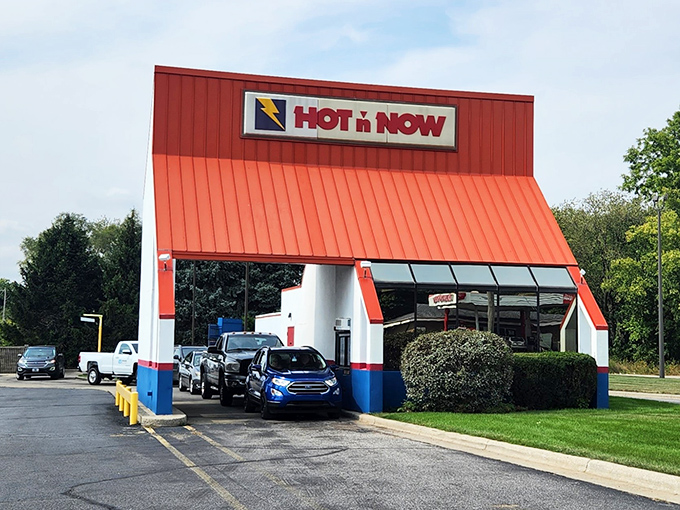 A beacon of burger bliss! Hot 'n Now's iconic red roof and retro charm beckon hungry travelers like a neon-lit oasis in the fast food desert.