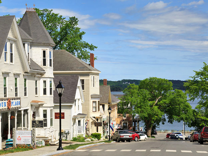 Castine: Where history and charm collide in a picture-perfect coastal tableau. This view showcases the town's stunning blend of colorful homes, lush trees, and sparkling blue waters.