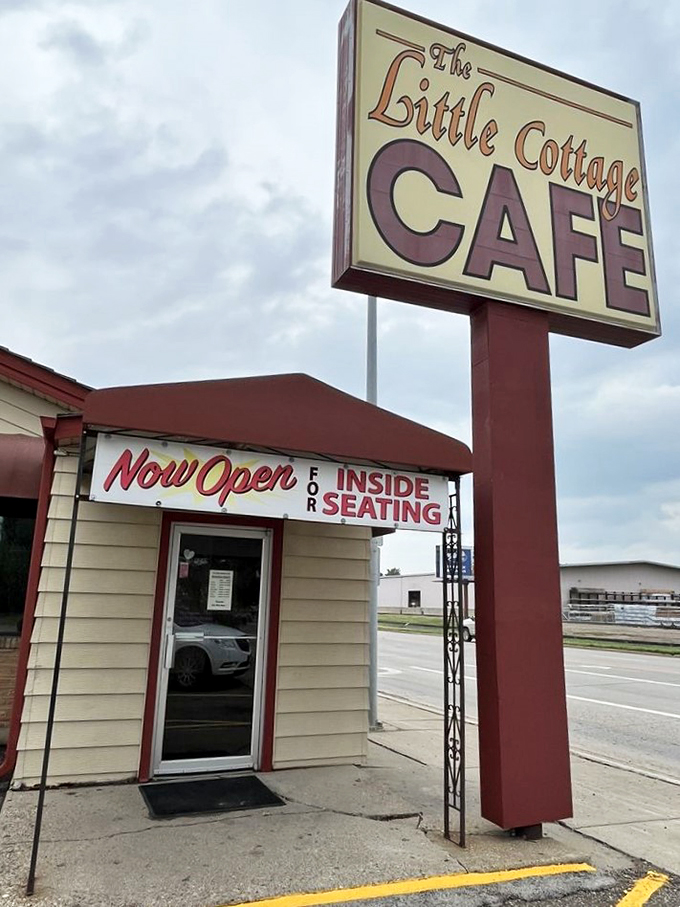 Welcome to flavor town! The Little Cottage Caf&eacute;'s sign promises big taste in a small package, like a culinary TARDIS waiting to be explored.