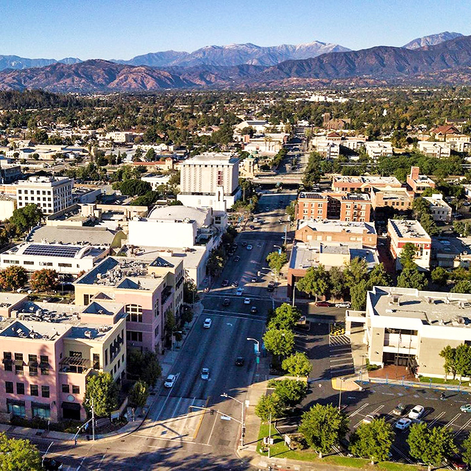Pomona: Where the mountains meet Main Street! This aerial view showcases the city's charming blend of urban life and natural beauty, like a California snow globe minus the snow.