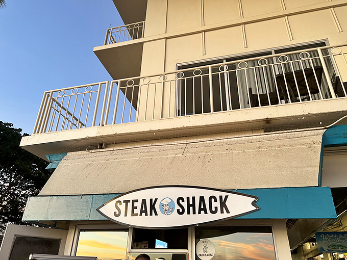 Surf's up, and so is your appetite! The Steak Shack's surfboard sign promises waves of flavor just steps from Waikiki Beach.