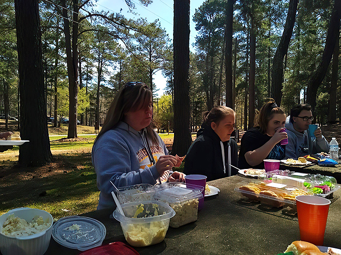 Picnic perfection in progress. These folks have mastered the art of outdoor dining, turning a simple meal into a feast fit for forest royalty.