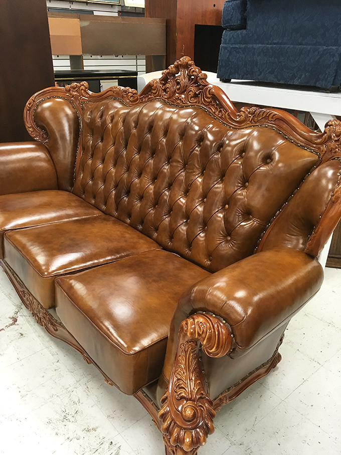 "The throne of thrift: Fit for a king (or at least a very fancy couch potato)." This ornate leather sofa screams 'Victorian parlor meets man cave.'