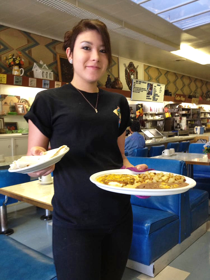 The image shows a restaurant interior with staff and diners, capturing the warm, bustling atmosphere of El Coronado.