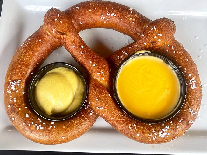 Twisted perfection! This pretzel is giving us a salty hug, complete with dipping sauces for that extra flavor kick.