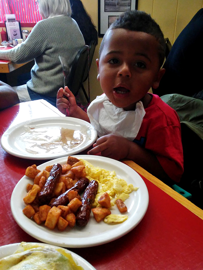 A young diner enjoying a hearty breakfast. His expression suggests he's discovered the secret to happiness: diner food!