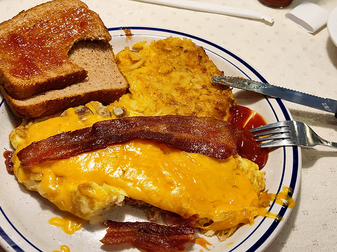An omelet that's more stuffed than your holiday turkey! This cheesy masterpiece, flanked by crispy bacon, is breakfast nirvana on a plate.