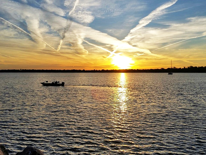"Nature's farewell party: BYOB (Bring Your Own Boat)." A stunning sunset paints the sky, while a lone boat bids the day adieu.