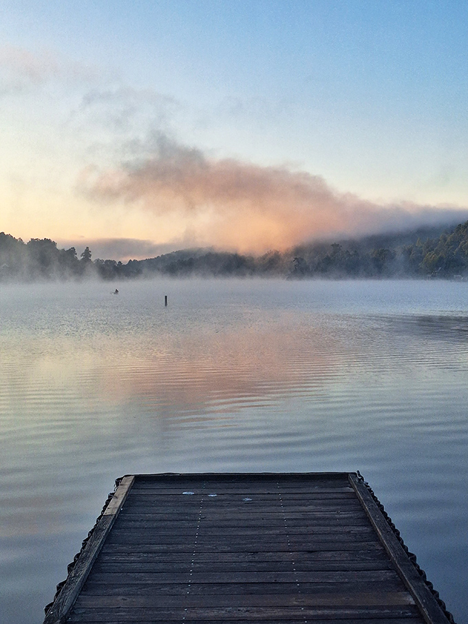 Misty morning magic on the lake. This ethereal scene is worth setting your alarm for &ndash; nature's own light show, no tickets required!