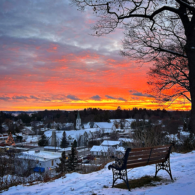 Sunset over Petoskey: A fiery sky paints the snow-covered town in warm hues. It's like God decided to outdo Bob Ross in creating happy little trees and clouds.