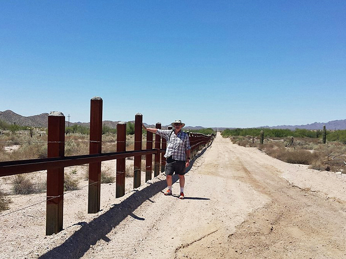 "Where's Waldo: Desert Edition?" Spot the lone explorer dwarfed by an endless fence stretching across the sun-baked Arizona landscape. A reminder that sometimes, the journey is the destination.