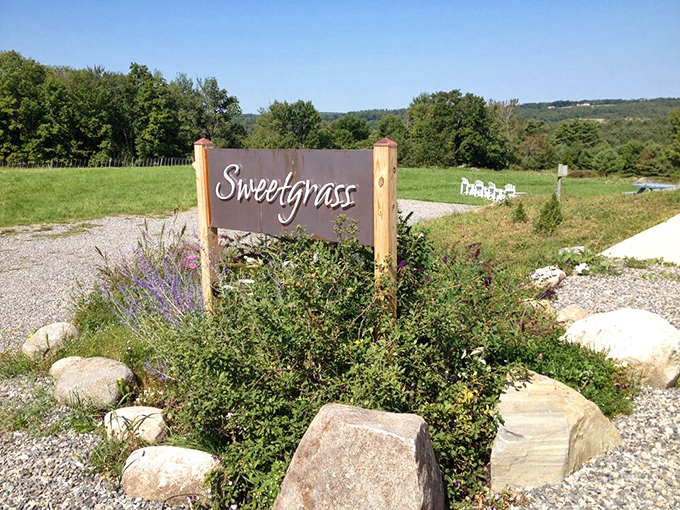 Mother Nature's own welcome mat: wildflowers and rocks frame the Sweetgrass sign, inviting you to a tasting adventure in Maine's picturesque countryside.