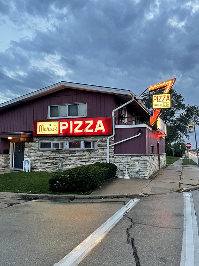 Neon dreams and pizza schemes! Maria's glowing sign is like a lighthouse, guiding hungry sailors to a safe harbor of cheesy delights.