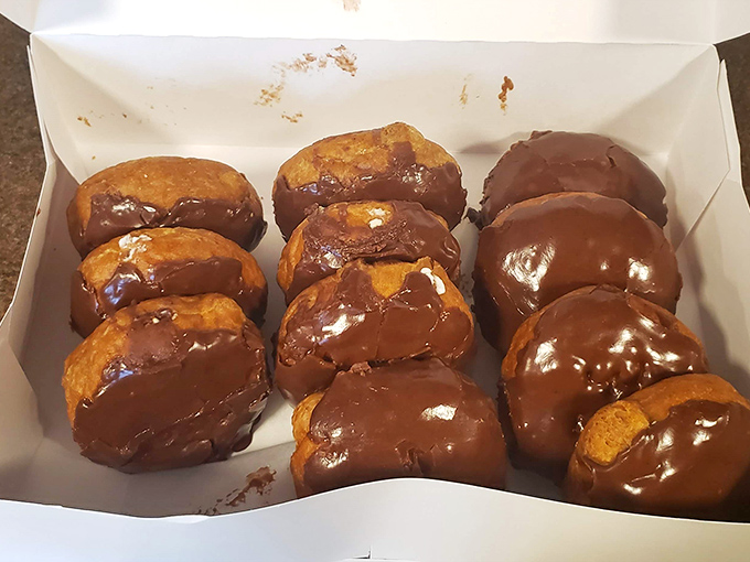 A dozen chocolate-glazed donuts nestled in their box like edible jewels &ndash; breakfast of champions or afternoon delight?