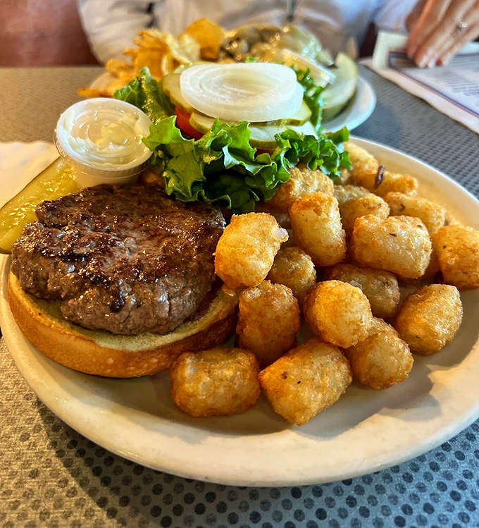 Burger bliss alert! This beefy beauty, flanked by golden tater tots, is the stuff food dreams are made of. Napkins at the ready, folks!