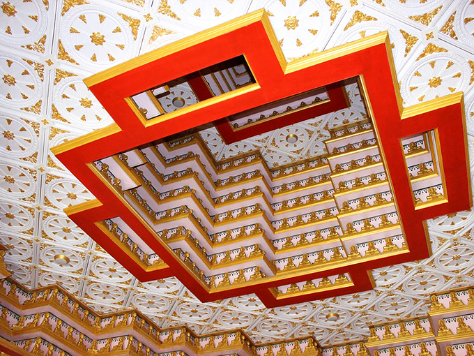 Look up and lose yourself in this mesmerizing ceiling. It's like a geometric galaxy of gold and red!