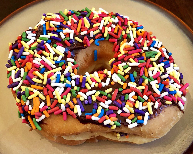 Sprinkle me silly! This donut's not just wearing jimmies, it's rocking a technicolor dreamcoat of sugary confetti.