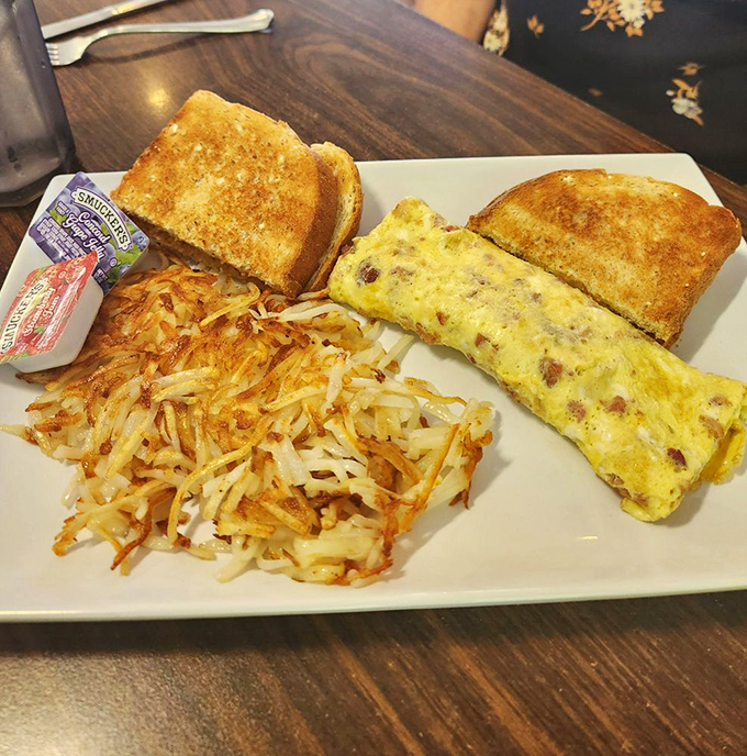Eggs-cellence on a plate! This ham and cheese omelet is so fluffy, it might float away if not for its crispy potato anchor. A breakfast of champions, indeed.
