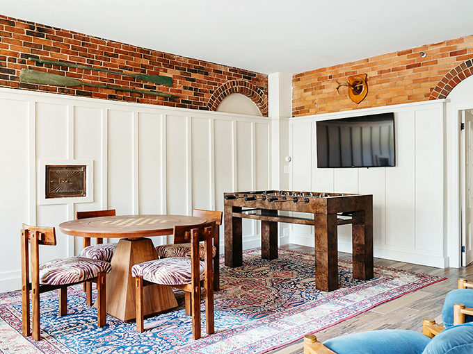 Game night just got an upgrade! This room screams "friendly foosball tournament" with a side of "I spy some exposed brick charm."
