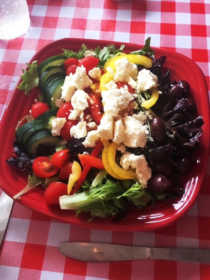 A Greek salad that would make Zeus jealous! Fresh veggies and feta create a colorful symphony on this red plate.