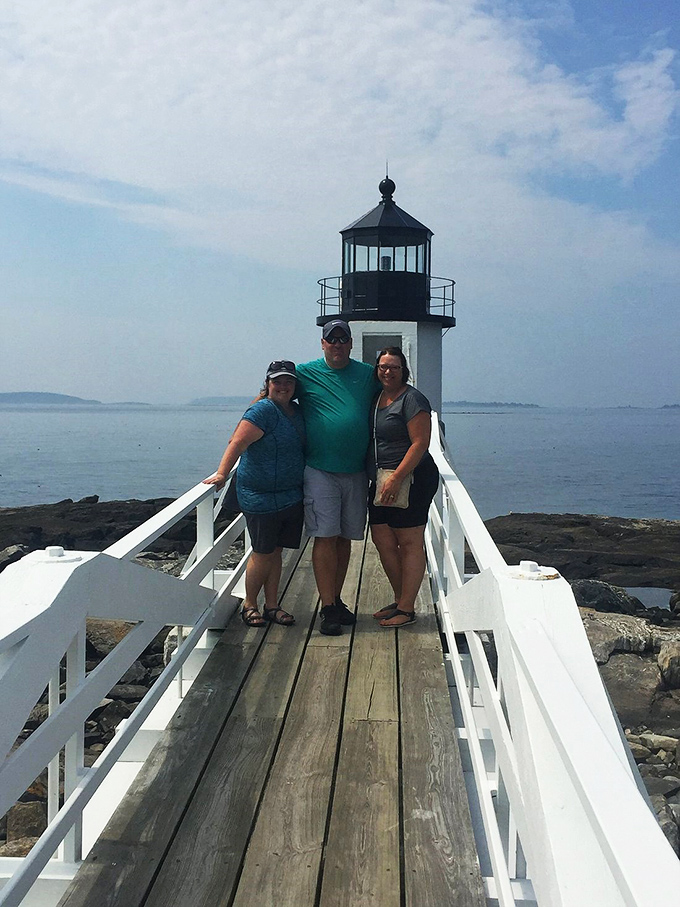 People explore the grounds near outbuildings at the lighthouse site.