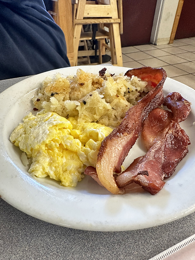 The breakfast trifecta: golden eggs, crispy potatoes, and bacon so perfect it should have its own Instagram. A plate of pure morning magic!