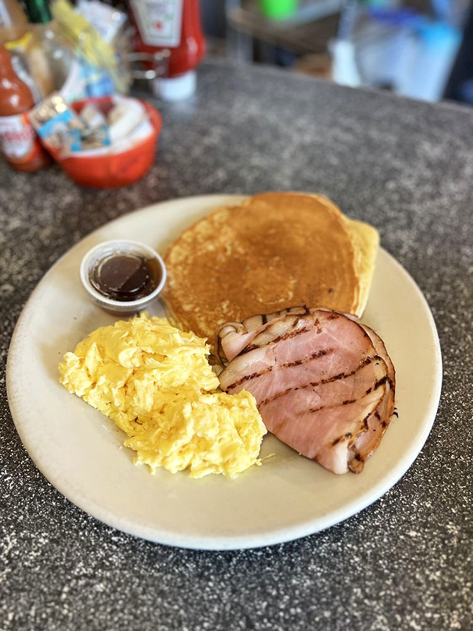 The holy trinity of breakfast: golden pancakes, fluffy scrambled eggs, and ham that could make a vegetarian reconsider.