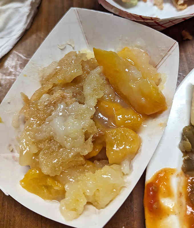 Warm peach cobbler with buttery crust and syrupy peaches melting into every bite