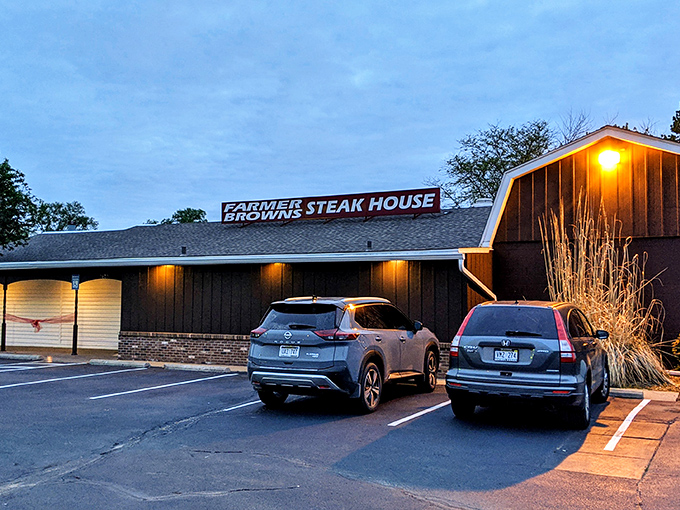 The unassuming exterior of Farmer Brown's Steak House stands like a beacon at dusk, promising carnivorous delights within its humble walls.