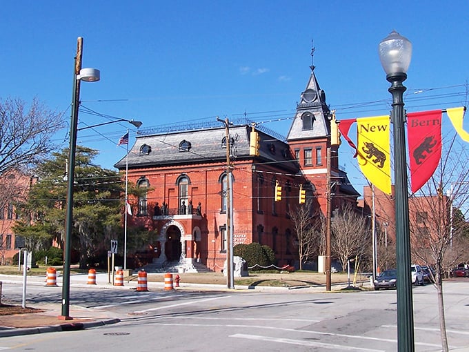 Take a stroll through historic New Bern, where you'll find charming brick architecture and vibrant banners under a clear blue sky.