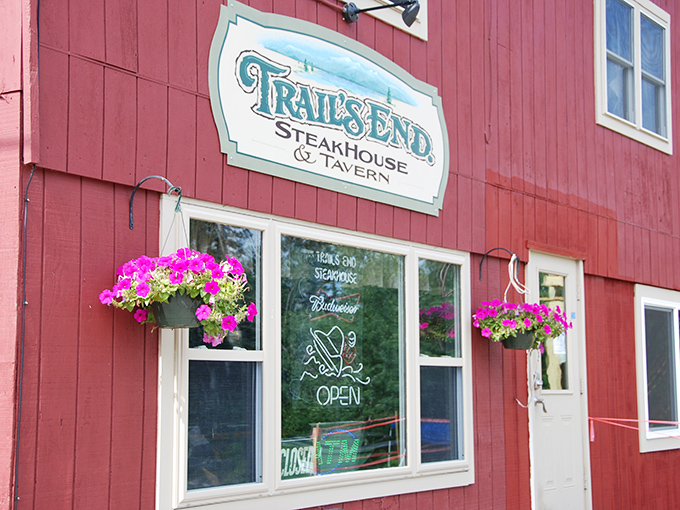 A red beacon of culinary delight! Trail's End Steakhouse stands proud, its rustic charm beckoning hungry travelers like a meaty lighthouse in the Maine wilderness.