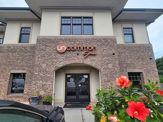 The stately brick facade of Uncommon Grill welcomes you with vibrant hibiscus flowers, promising an experience that's anything but ordinary.