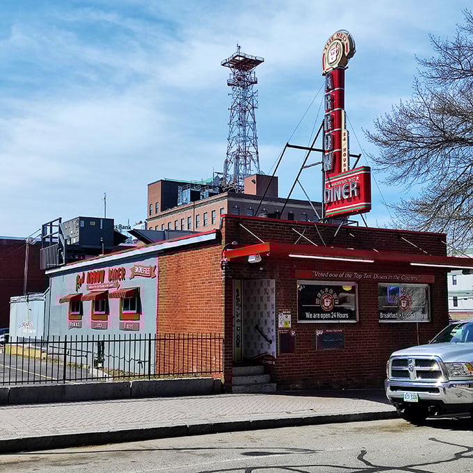 A beacon of comfort food! The Red Arrow Diner's iconic sign promises 24/7 deliciousness, standing tall against Manchester's skyline like a culinary lighthouse.
