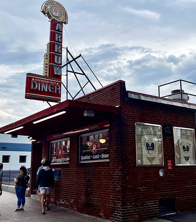 A beacon of comfort food! The Red Arrow Diner's iconic sign promises 24/7 deliciousness, standing tall against Manchester's skyline like a culinary lighthouse.