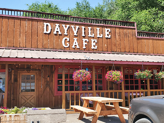 The wooden facade of Dayville Cafe stands proudly against the Oregon sky, hanging flower baskets adding splashes of color like nature's welcome committee.