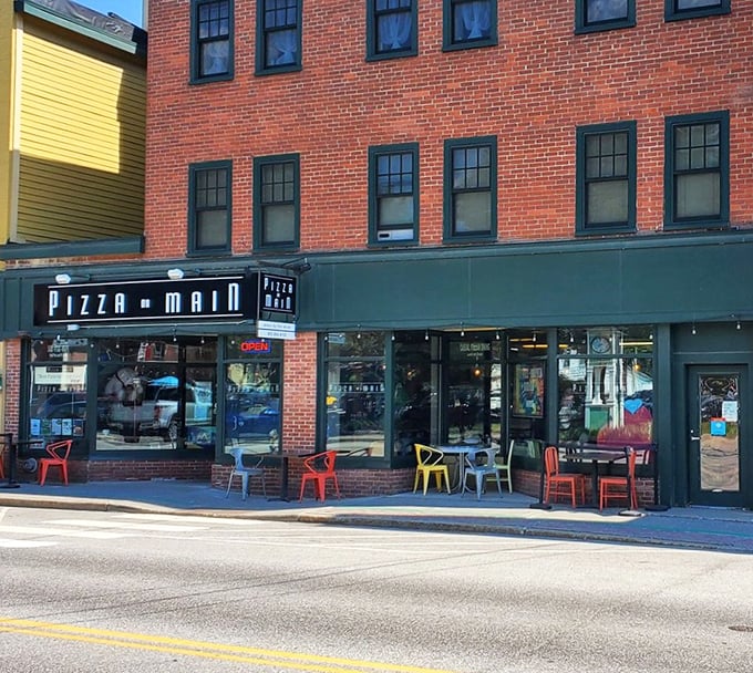 A slice of small-town charm! Pizza on Main's brick facade and colorful chairs invite you to savor a taste of Vermont hospitality.